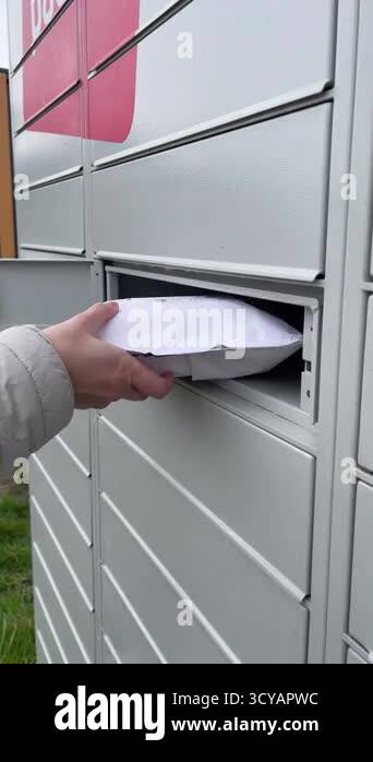 Close-up of a hand placing a parcel into a parcel locker and closing ...