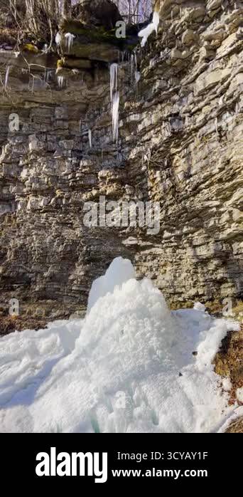 Frozen waterfall with large icicles in spring at dawn in the sun with ...