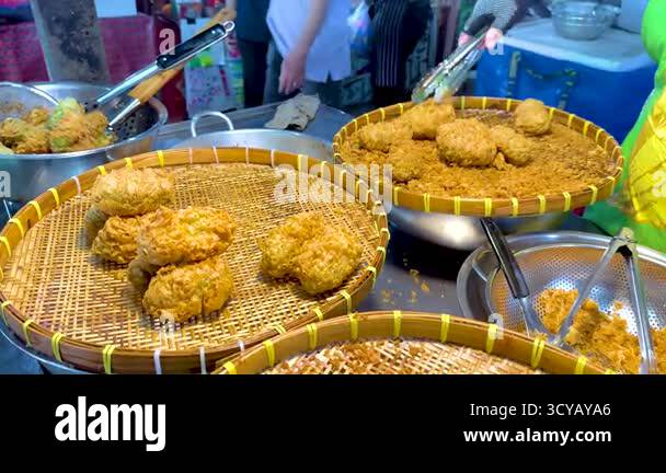 Vendor preparing crispy deep fried rice cakes at floating market stall ...