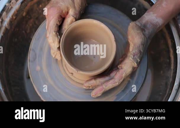 Potter shaping clay bowl on a wheel 4k video. Clay spins gently under ...