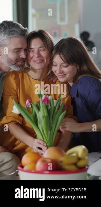 Family trio of happy parents and their adult daughter embracing ...