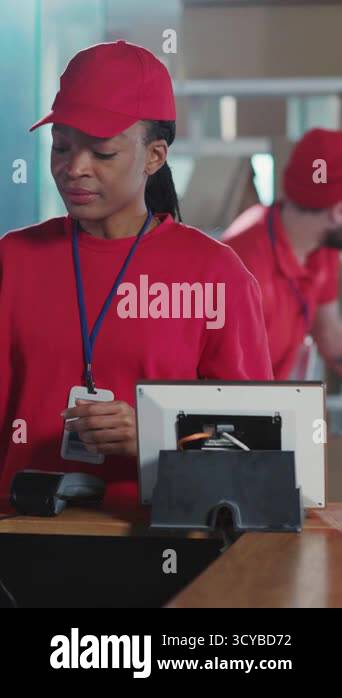 Two multi-ethnic courier workers in red uniform working in modern ...