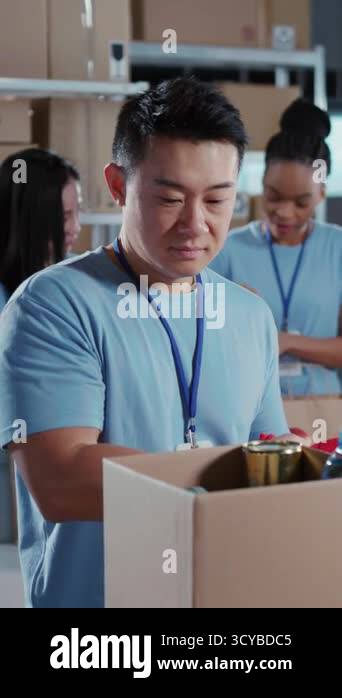 Multi-ethnic team of volunteers collaborating in workshop. Chinese male ...