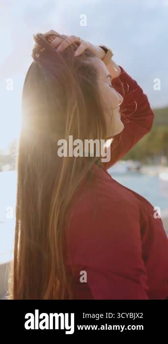 Outdoor portrait happy caucasian young pretty woman stroking her hair ...