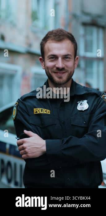 A confident police officer stands by a police car, exuding ...