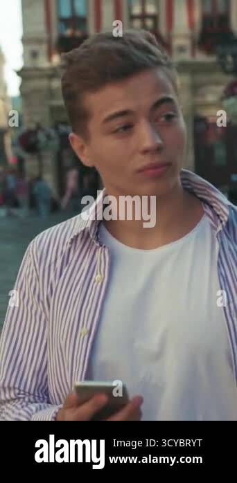 Face young happy man walk on street use phone look around smile ...