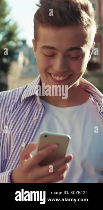 Close up face young happy man walk on street use phone look around ...