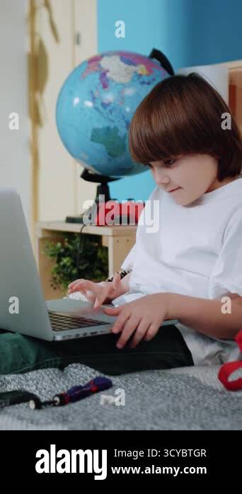 A young boy focused on his laptop, surrounded by educational tools and ...