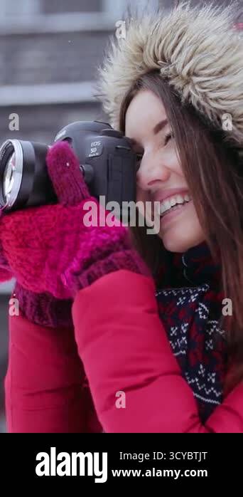 A cheerful woman in a red jacket captures moments with her camera, displaying her passion for ...