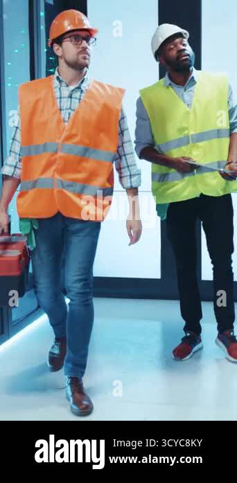 Two skilled technicians wearing safety vests are working together ...