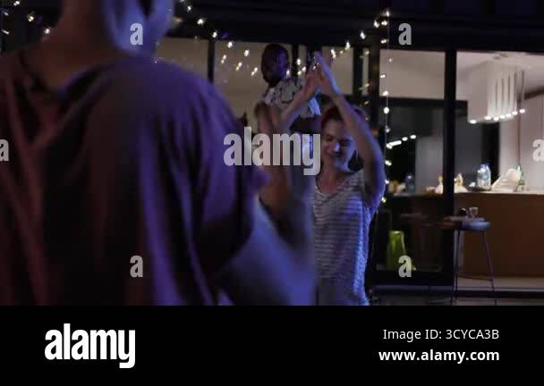 Attractive friends dancing together on the dance floor at home. Hanging ...