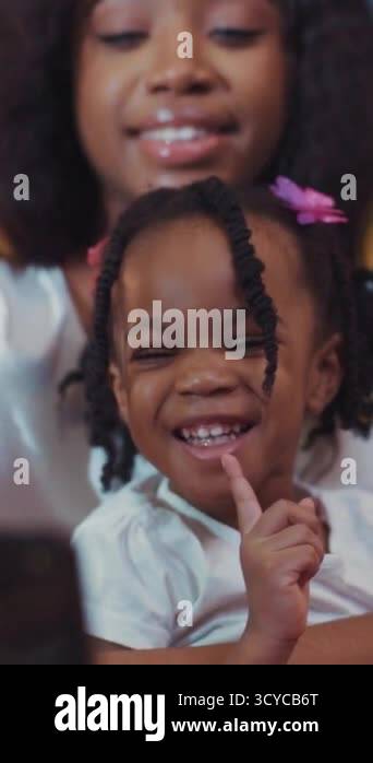 A woman cradles a smiling little girl with a pink flower in her hair ...