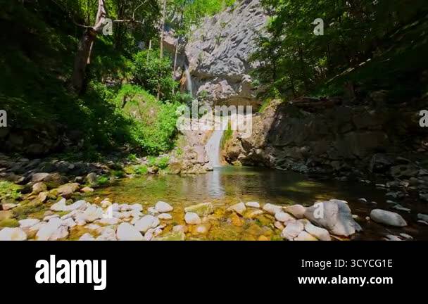 Aerial video of a scenic waterfall cascading down a rocky mountain ...