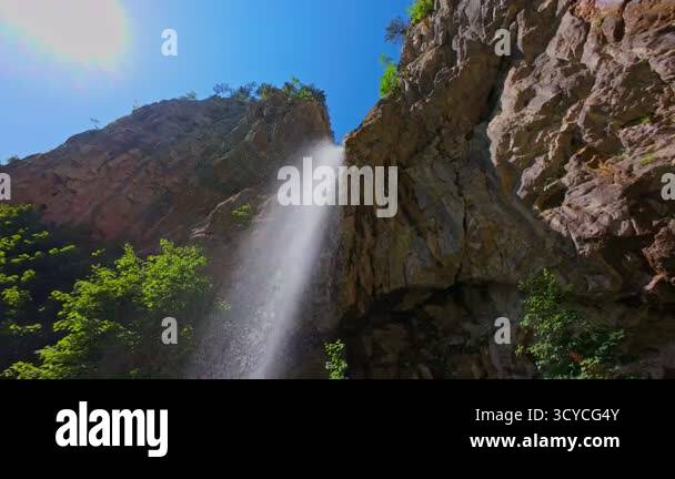 Aerial video of a scenic waterfall cascading down a rocky mountain ...