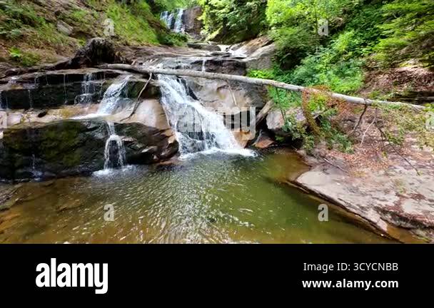 Aerial video of a beautiful waterfall flowing over rocks in lush green ...