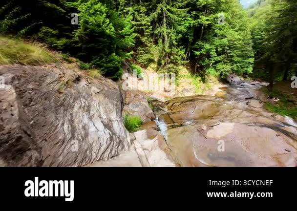 Aerial video of a beautiful waterfall flowing over rocks in lush green ...