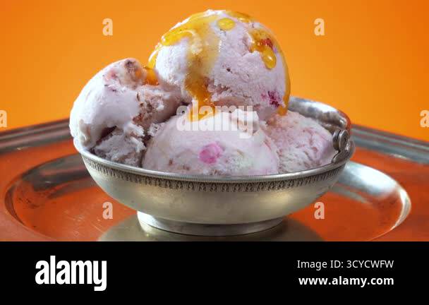 Sweet ice cream in a metal, silver container slowly rotates around its ...