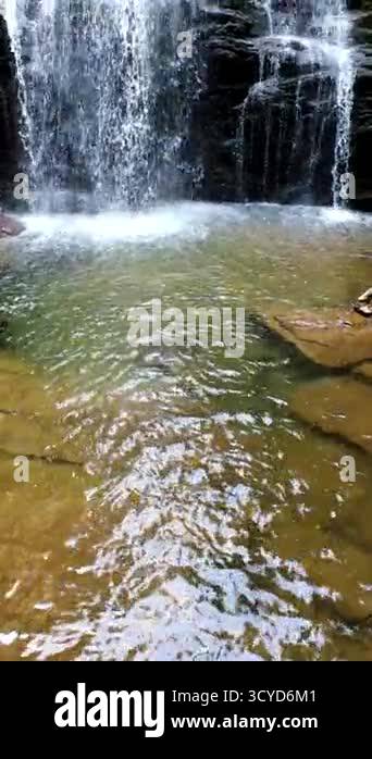 Aerial video of a beautiful waterfall flowing over rocks in green ...