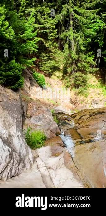 Aerial video of a beautiful waterfall flowing over rocks in green ...