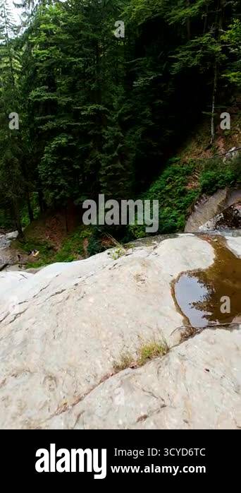 Aerial video of a beautiful waterfall flowing over rocks in green ...