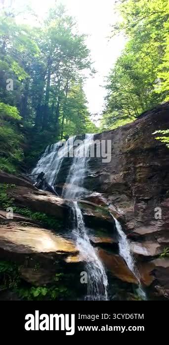 Aerial video of a beautiful waterfall flowing over rocks in green ...