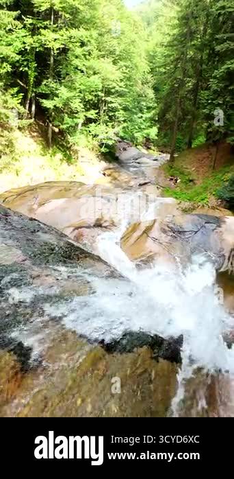 Aerial video of a beautiful waterfall flowing over rocks in green ...