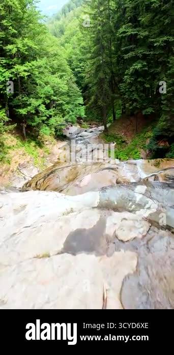 Aerial video of a beautiful waterfall flowing over rocks in green ...