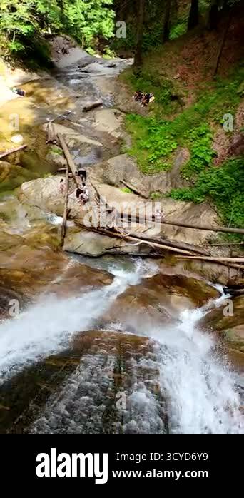 Aerial video of a beautiful waterfall flowing over rocks in green ...