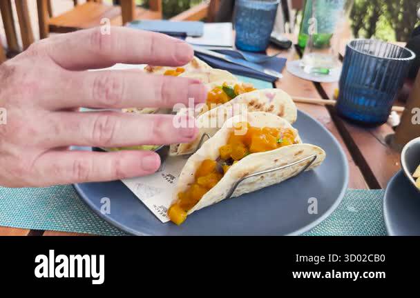 Person grabbing fish taco at outdoor resort restaurant dining table ...