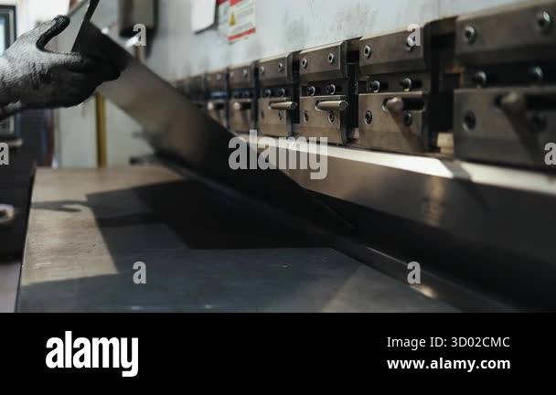 Close-up view of a metalworker operating a hydraulic press brake ...