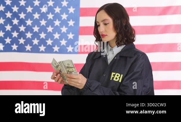 Woman FBI agent counts dollar bills against American national flag ...