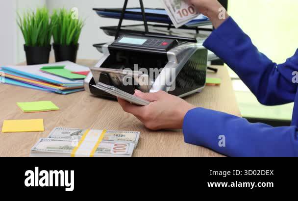 Woman hand puts hundred dollar bills into money counting machine at ...