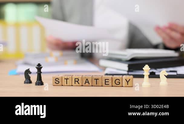 In a bright workspace, a person reviews papers and chess pieces while ...