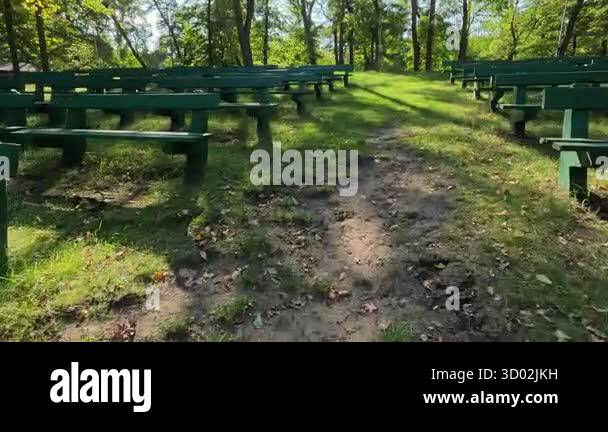Walking uphill along a grassy path between rows of green benches in a ...