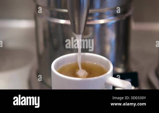 Adding milk to a cup of black tea. White and brown swirling. Closeup ...