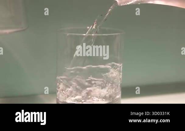High speed shot close up of clear mineral water pouring into drinking ...