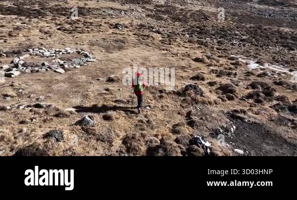 Lone hiker with a backpack and trekking clothes across a barren ...
