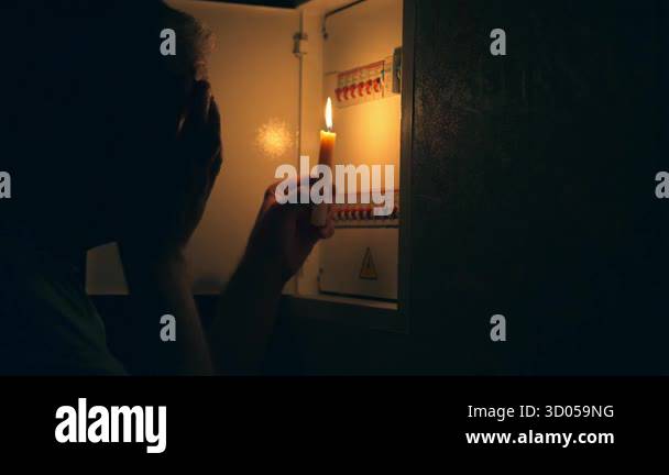 Blackout, No electricity. Man with a candle in the dark examines the ...
