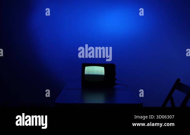 Retro television set with a glowing screen sits on a table against a ...