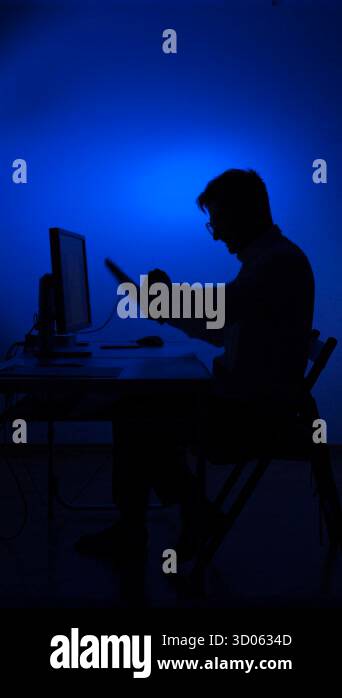 vertical video Mans silhouette is hitting a computer keyboard in ...