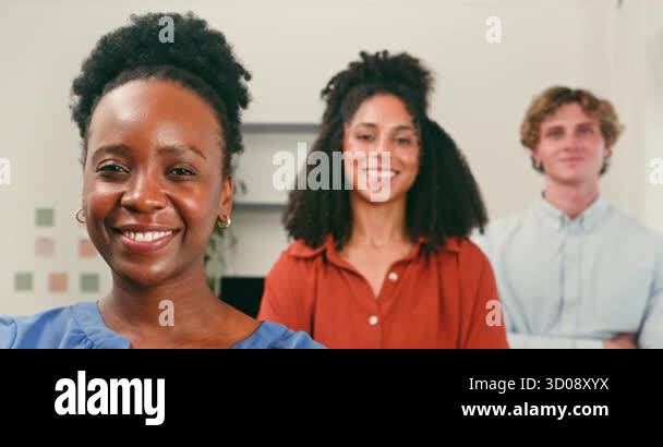 A diverse team of young professionals smiles confidently at the camera ...