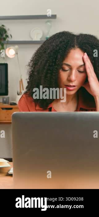 A young woman experiences a headache and stress while concentrating on ...