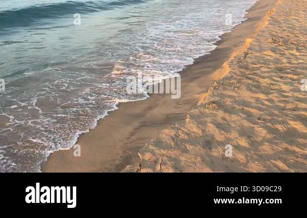 Rhythmic motion of gentle waves washing ashore on a sandy beach. The ...