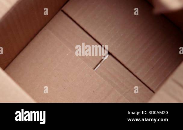 Hand placing crumpled paper filler into empty cardboard parcel box ...