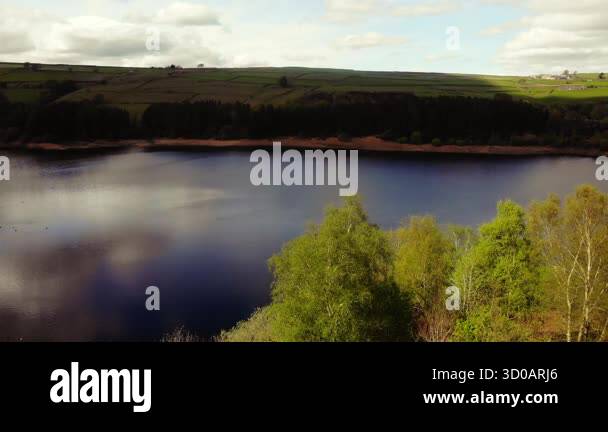 Trees and farmland surround lake in Peak District National Park blue ...