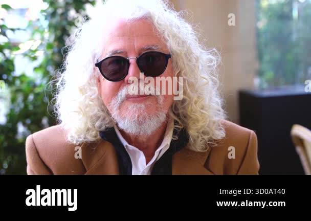 Close up portrait of senior man with white curly hair and sunglasses ...
