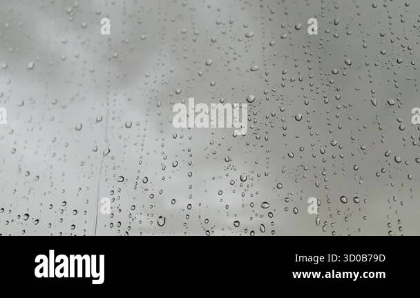 Raindrops on glass against a cloudy sky create a beautiful, natural ...