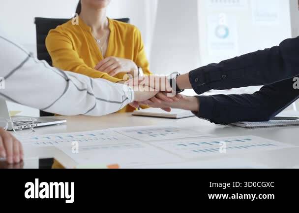 Business team members are joining hands together over documents on a ...
