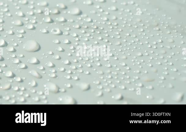 Small water droplets collect on a flat surface creating a gentle ...