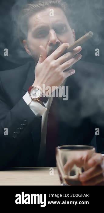 A man dressed in a suit smokes a cigar while surrounded by soft smoke ...